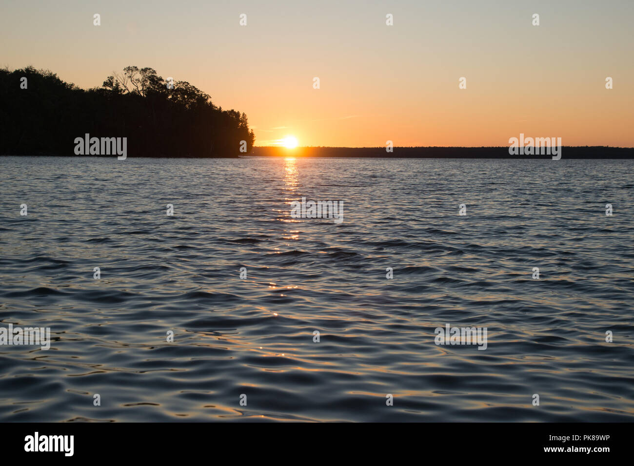 Lake Manitou shoreline sunset landscape with cedar trees and orange sky ...