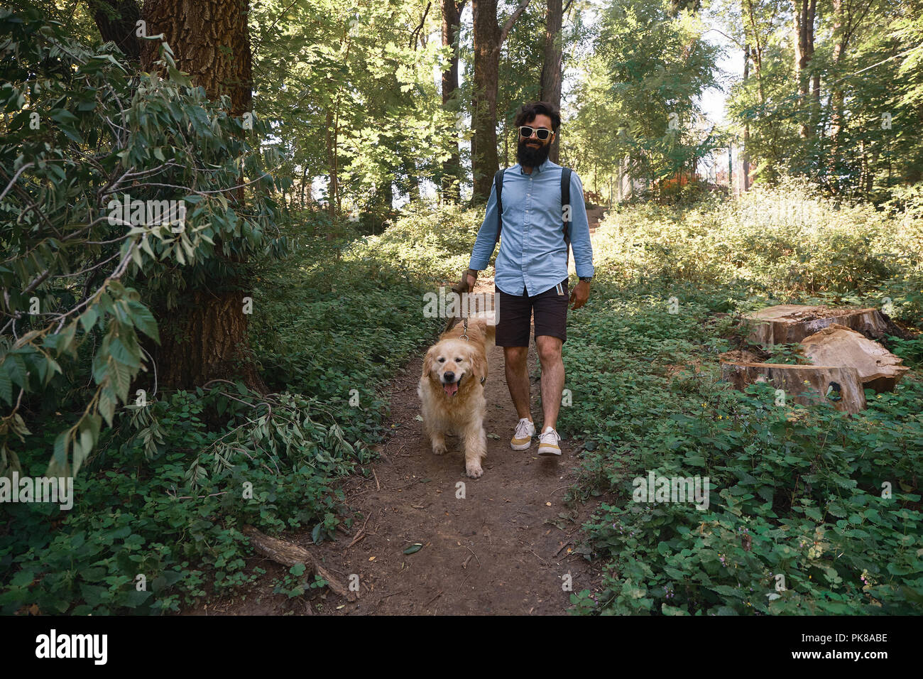 Handsome man walking his dog in the woods following a path. Happy ...