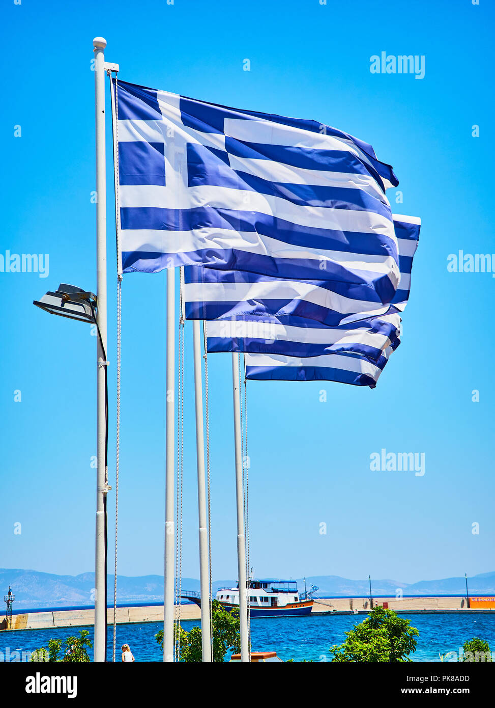 Four official flags of Greece waving on a blue sky with a seascape in ...
