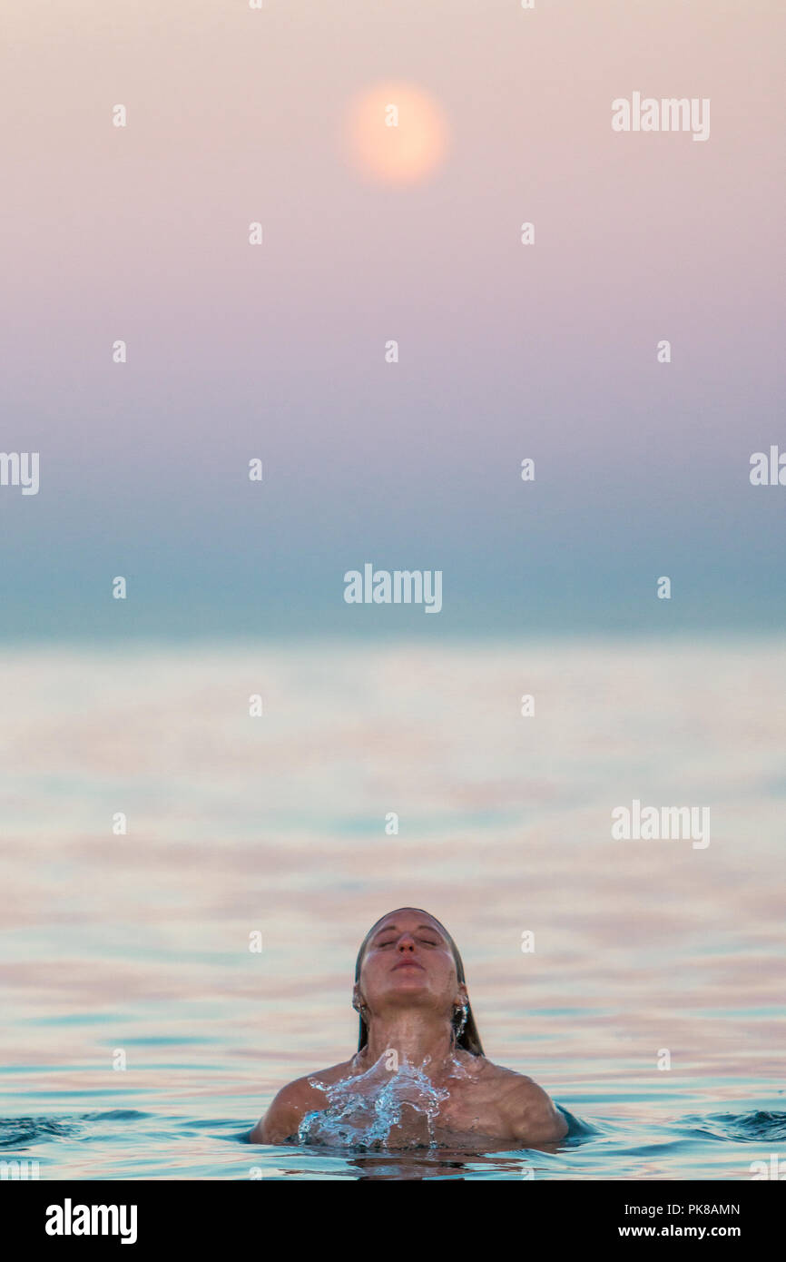 Caitlin bursting out of the water under the blood moon Stock Photo - Alamy
