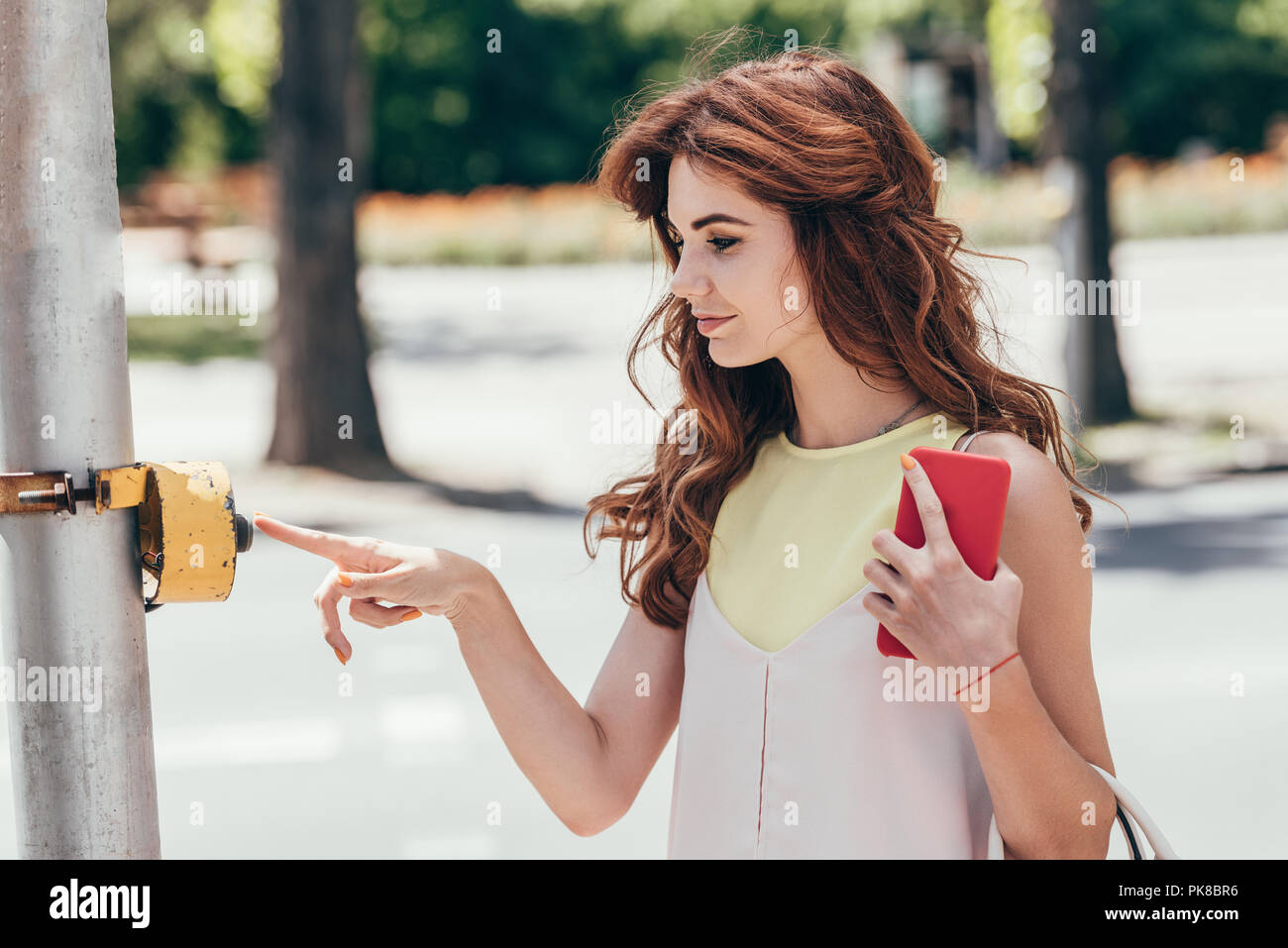 side view of young woman pressing button on pedestrian crossing Stock ...