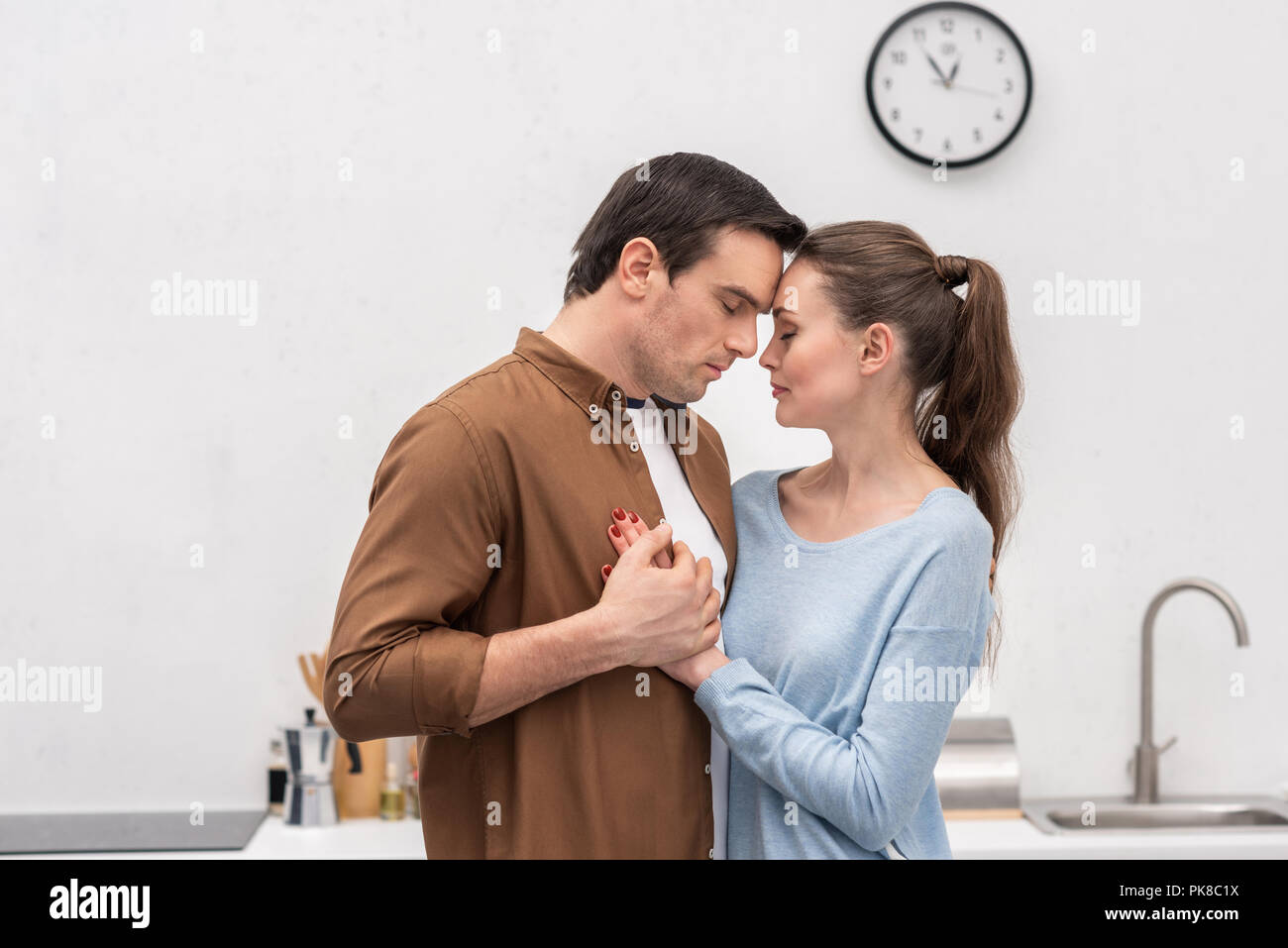 beautiful adult couple cuddling at home in front of white brick wall ...