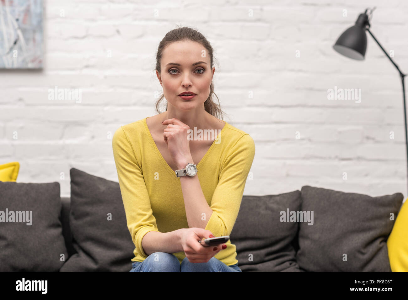 beautiful adult woman with remote control watching tv while sitting on ...