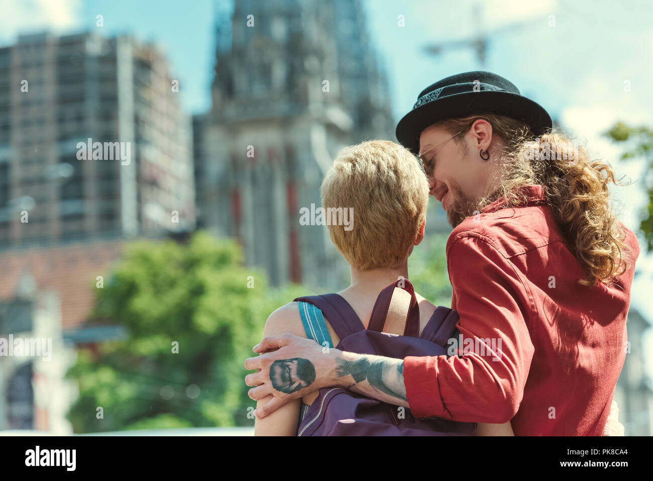 back view of stylish couple of travelers hugging in city Stock Photo ...