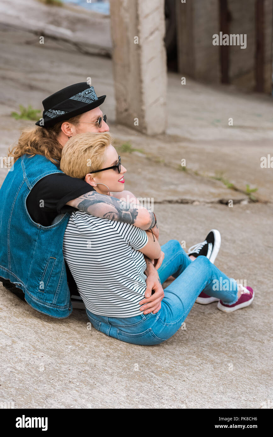 side view of boyfriend with tattoos hugging stylish girlfriend and they ...
