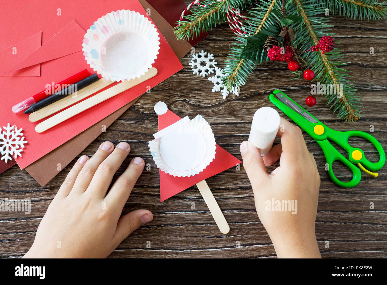The child glues the parts Christmas Santa stics puppets. Handmade ...