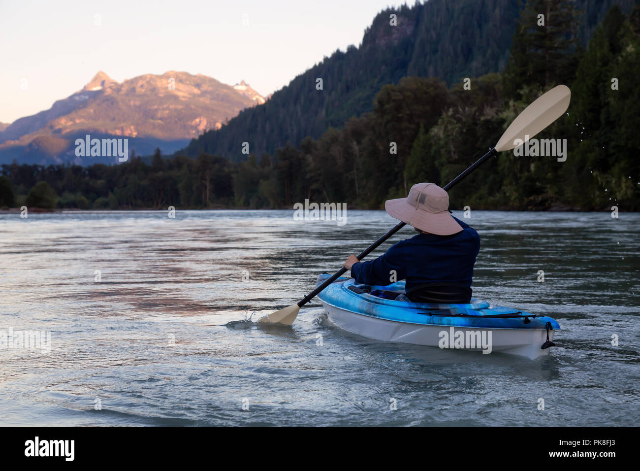 Kayaking in a river surrounded by Canadian Mountains during a vibrant ...