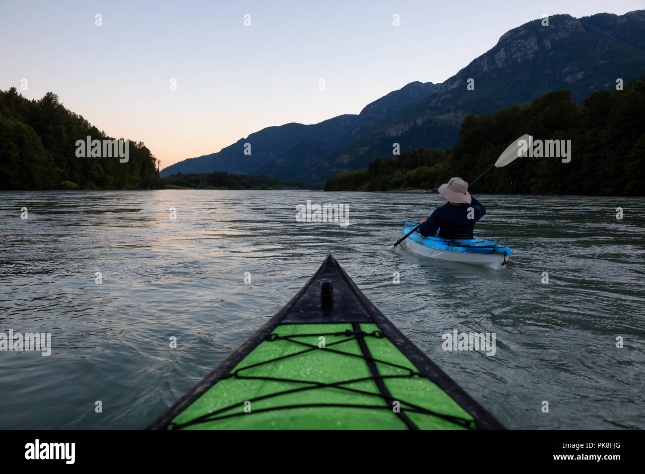 Kayaking in a river surrounded by Canadian Mountains during a vibrant ...