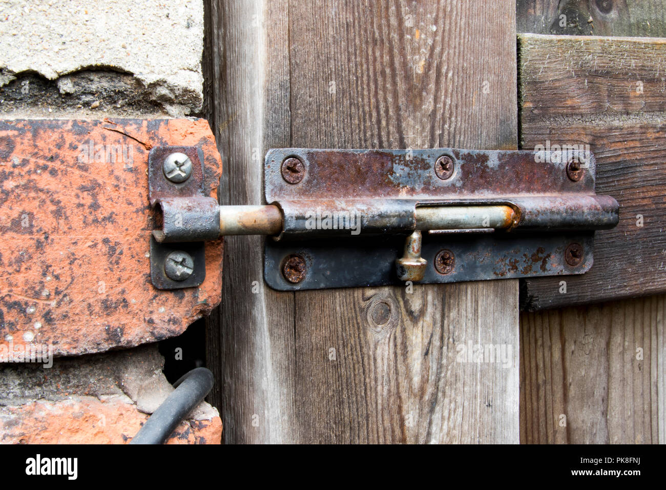 Rusty gate lock. Wood fence gate and house brick close up Stock Photo ...
