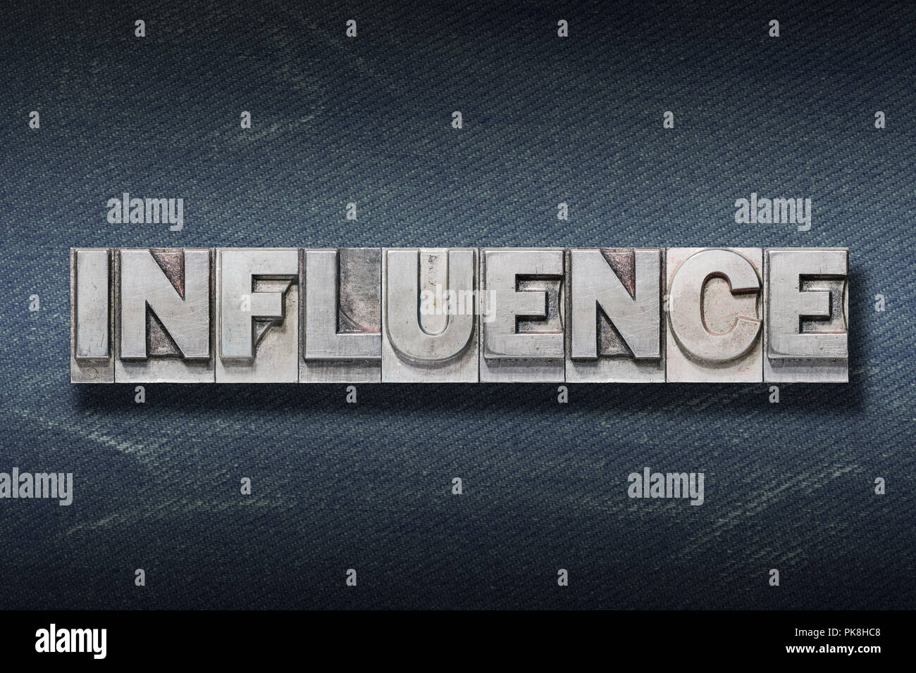 influence word made from metallic letterpress on dark jeans background ...