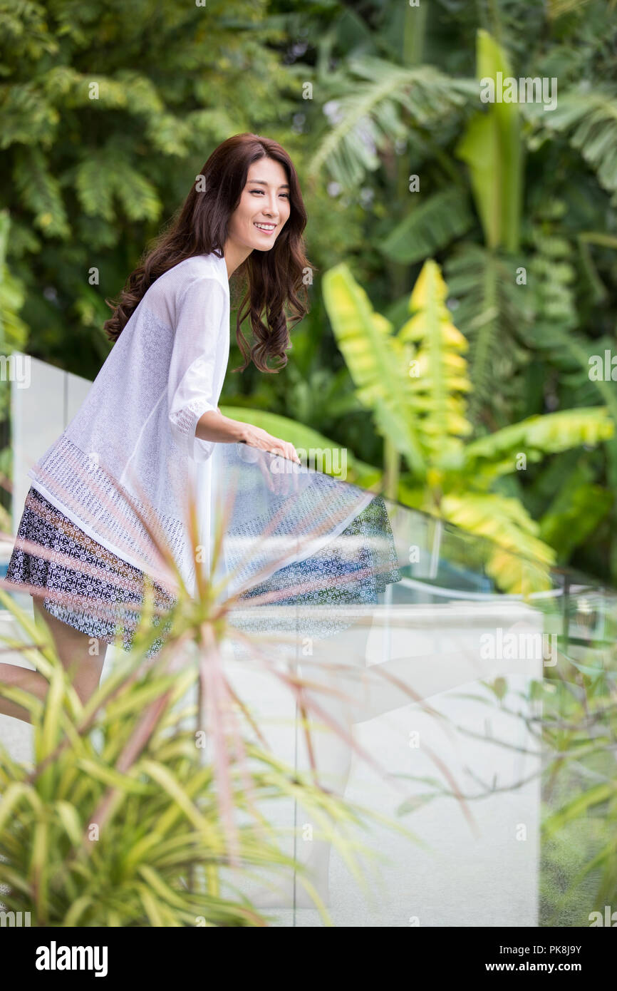 Happy young Chinese woman relaxing on balcony Stock Photo - Alamy
