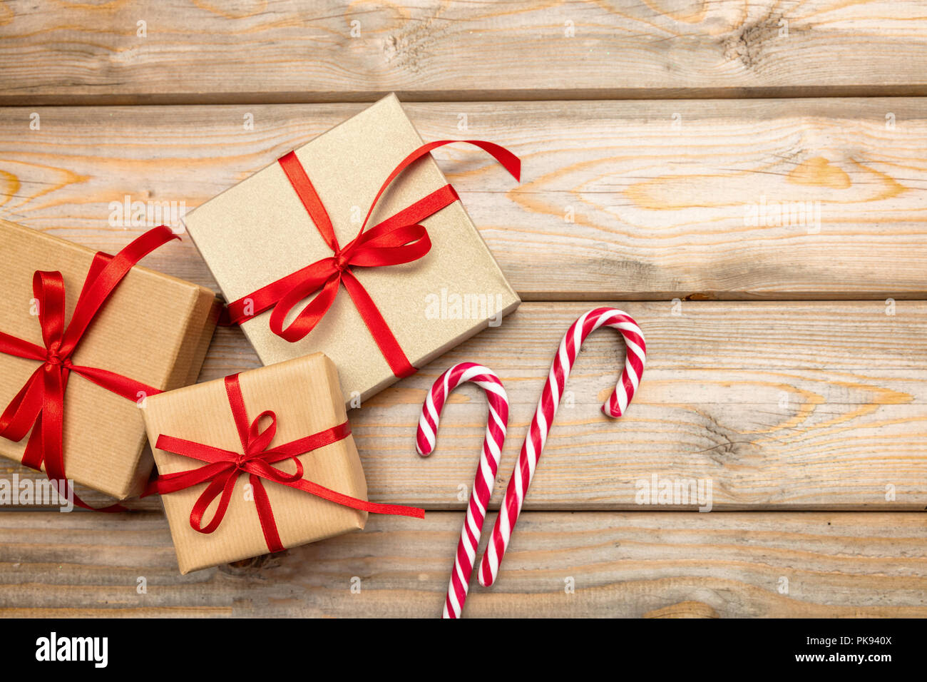 Christmas time. Gift boxes with red ribbon and candy canes on wooden ...