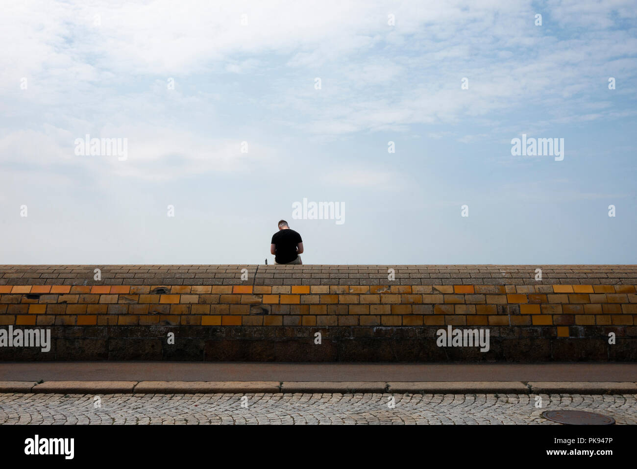 Sitting man at wall Stock Photo - Alamy