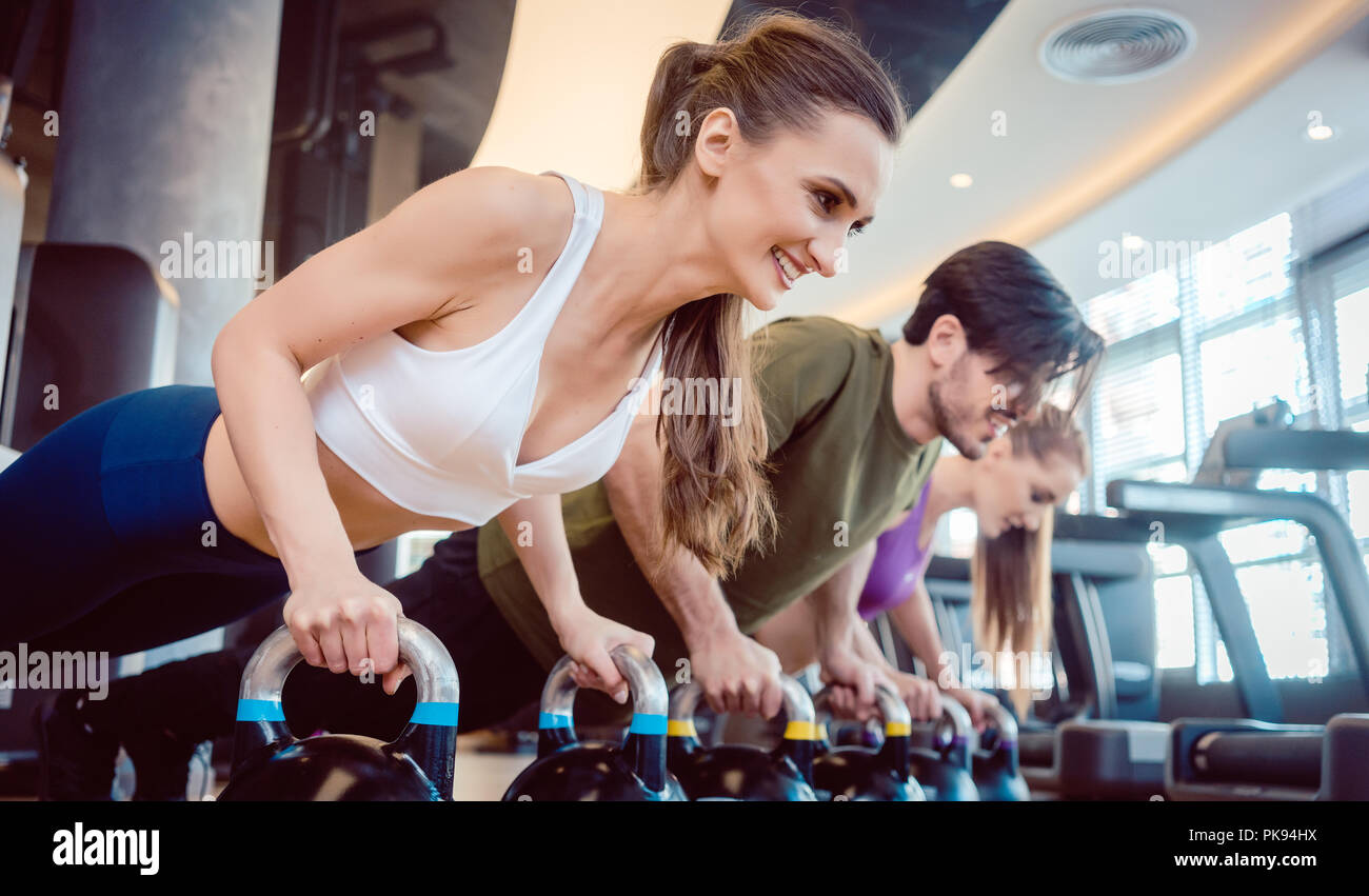Three young people doing the kettlebell plank challenge Stock Photo - Alamy