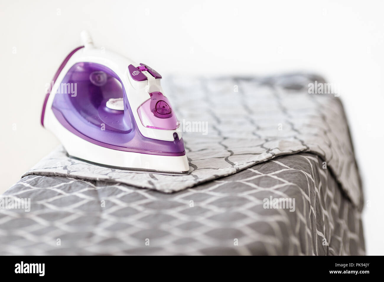Iron on ironing board on light home interior background. Ironing bed ...