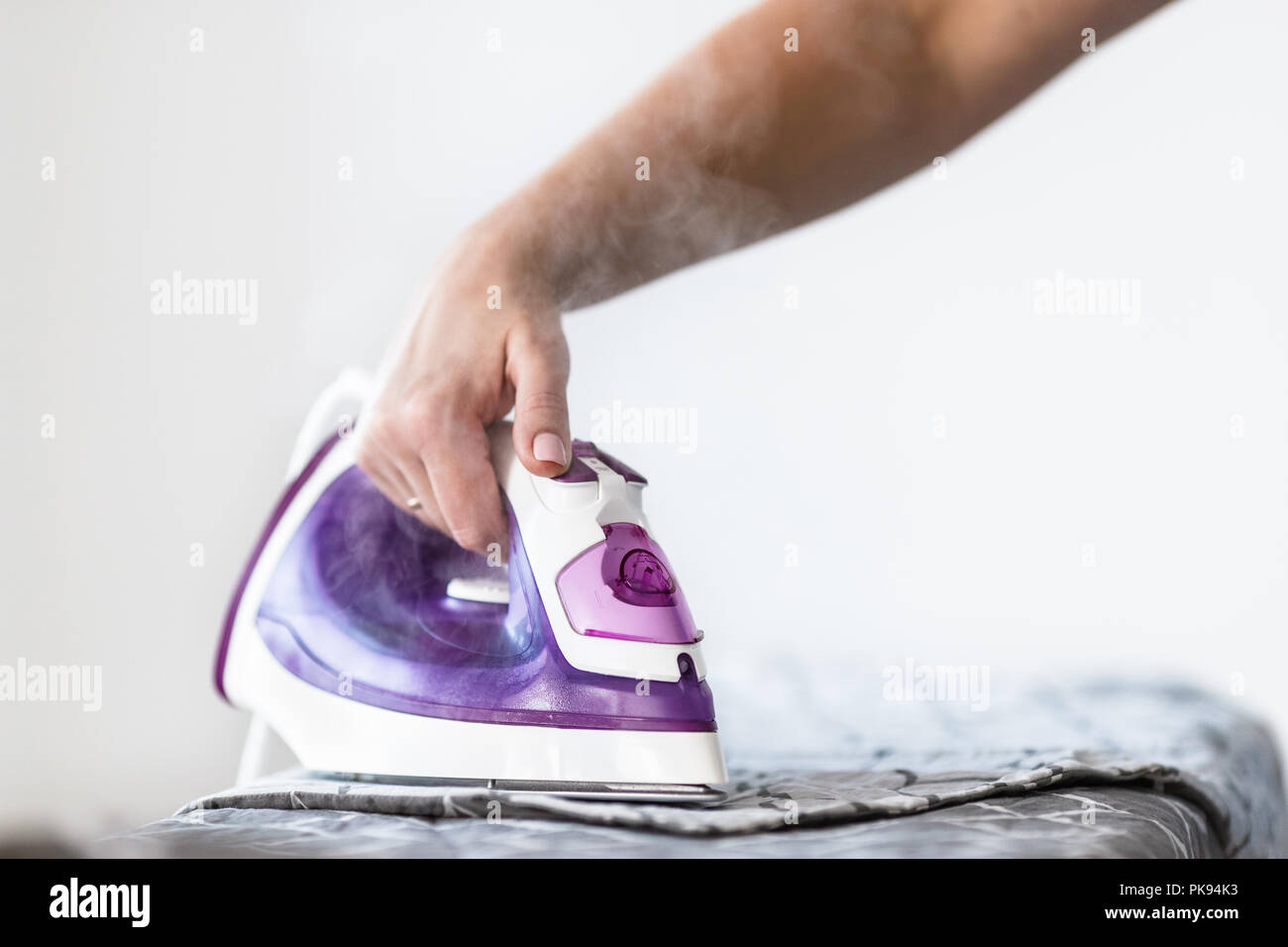 Iron on ironing board on light home interior background. Ironing bed ...