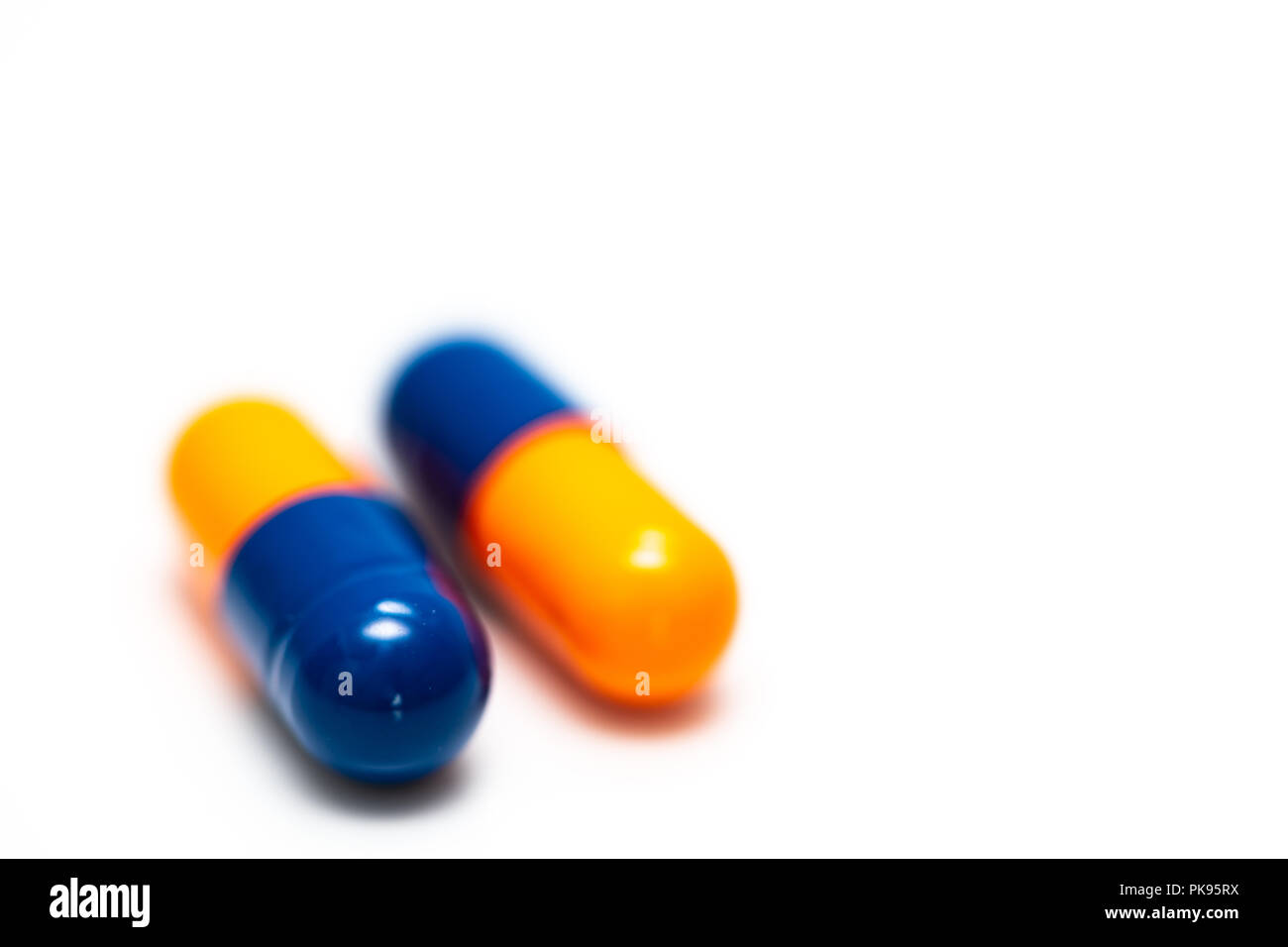 Blue & Orange drug medicine pills colored capsules closeup on white ...