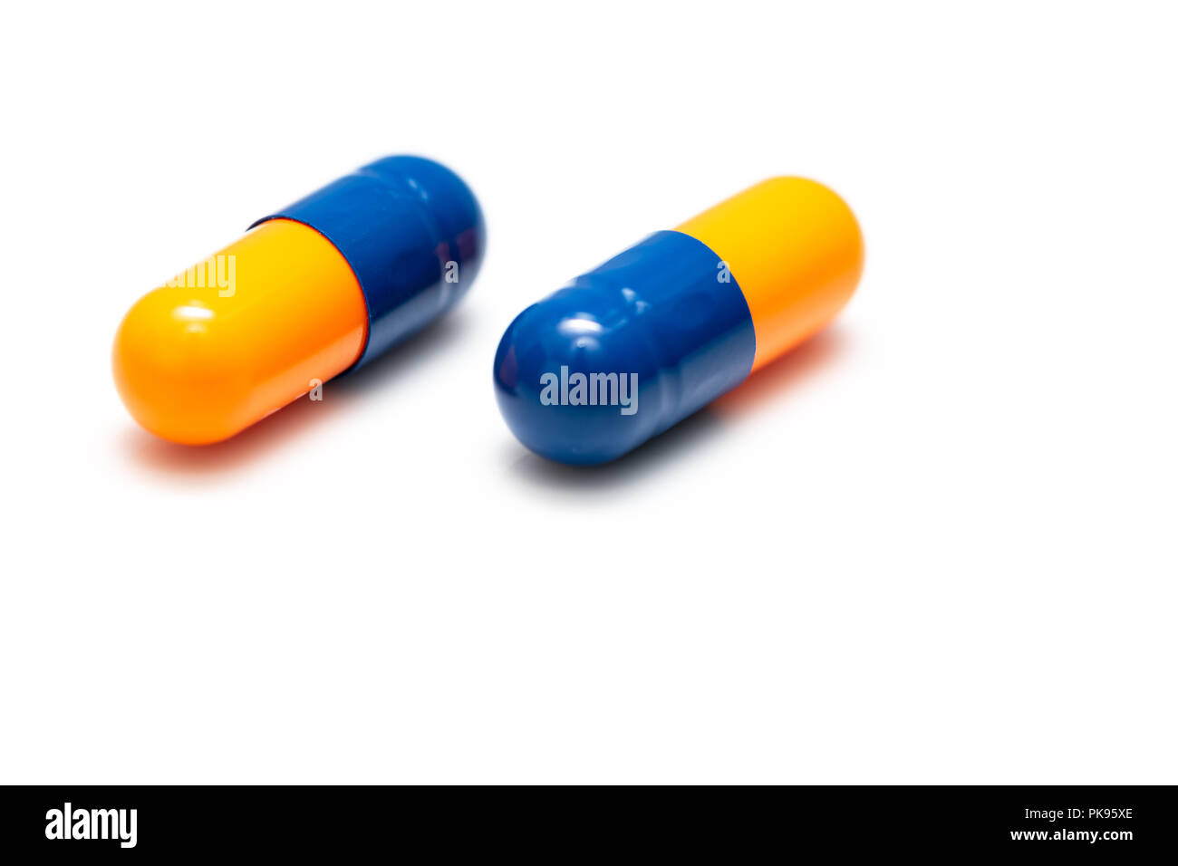 Blue & Orange drug medicine pills colored capsules closeup on white ...