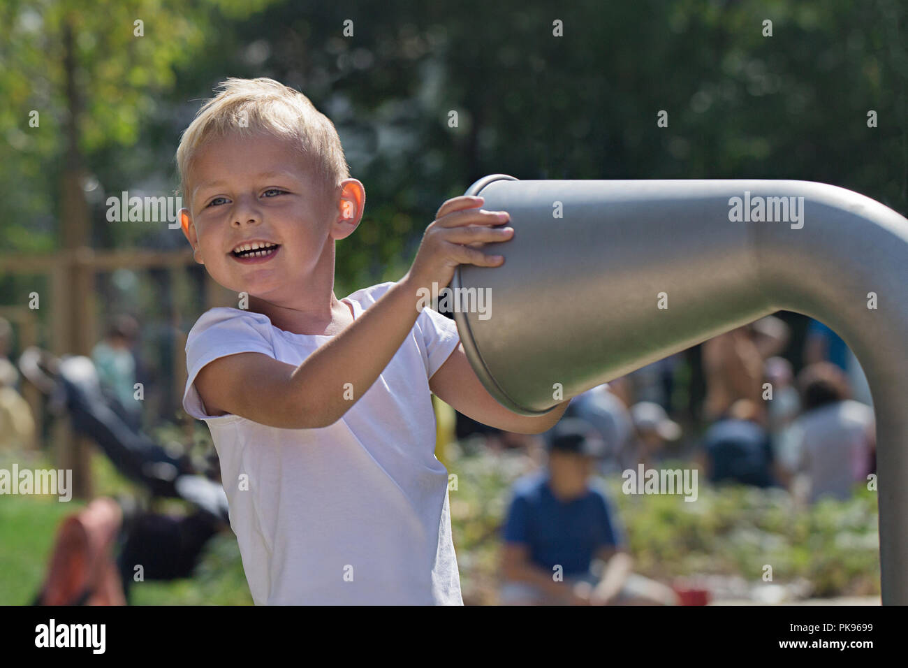 A little boy is talking in a metal pipe for talks in the playground on ...