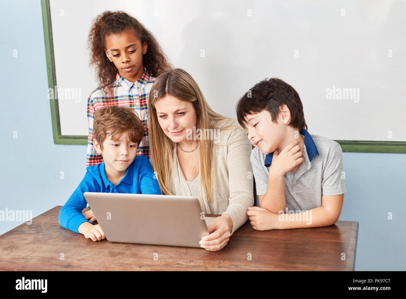 Teacher and elementary school students learn together at the laptop ...