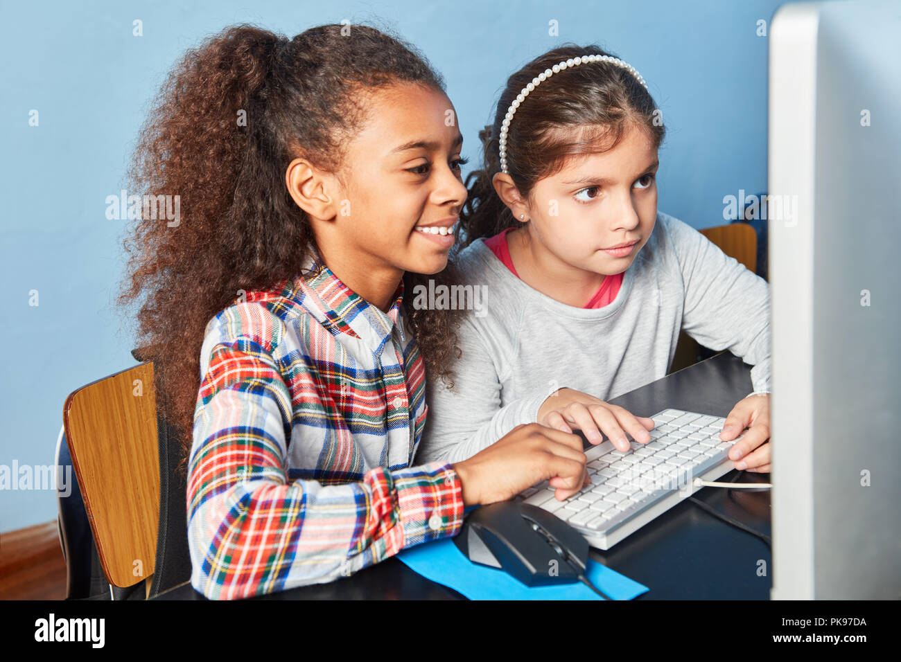Two girls learn together at the computer in computer science lessons ...