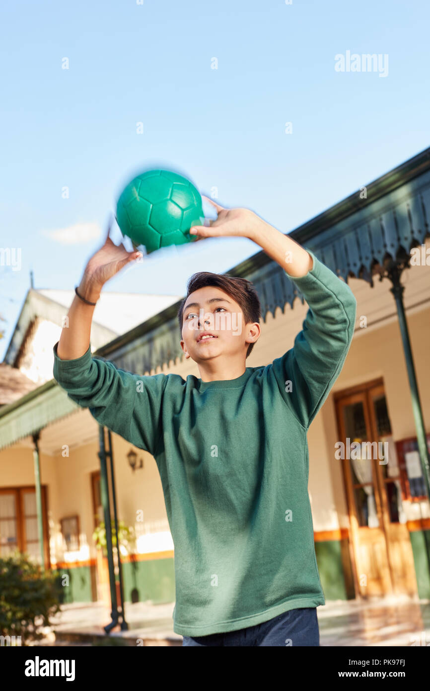 Boy as a student throws a ball in the schoolyard in physical education ...