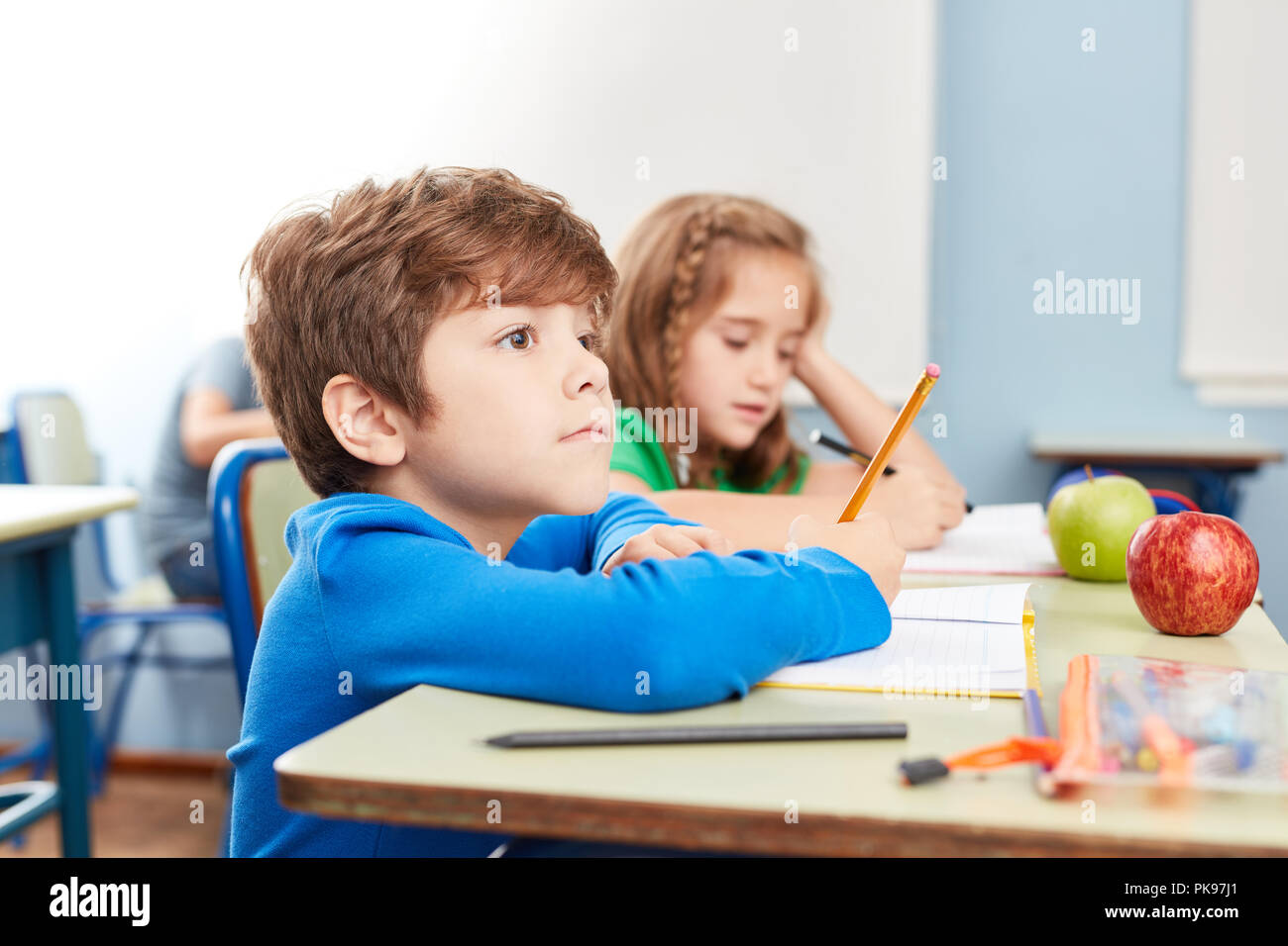 Attentive boy as a student at dictation or a test in the classroom ...