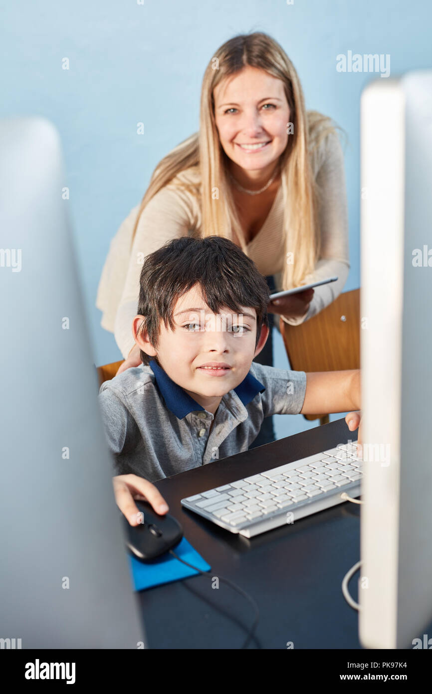 Boy as a student with a teacher at the computer in computer science ...