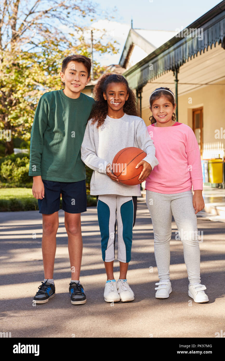 Three multicultural elementary school students as a team in basketball ...