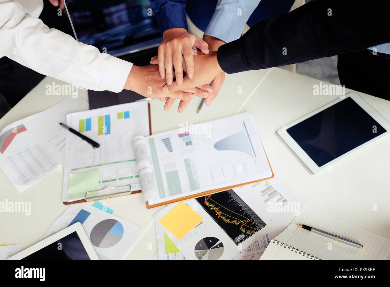 Business people putting their hands on top of office desk cooperation ...