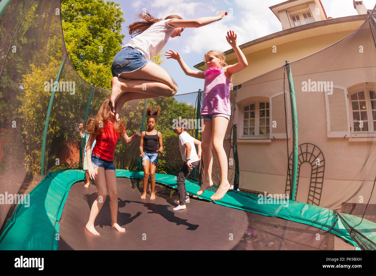 Happy friends bouncing on the outdoor trampoline Stock Photo - Alamy