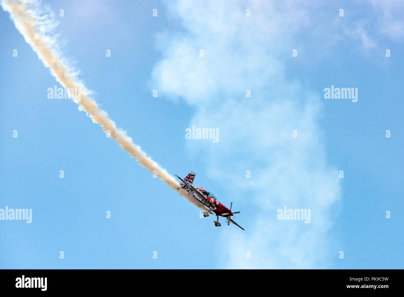 A G-Force Aerobatics Extra 300 trails a plume of white smoke as it ...