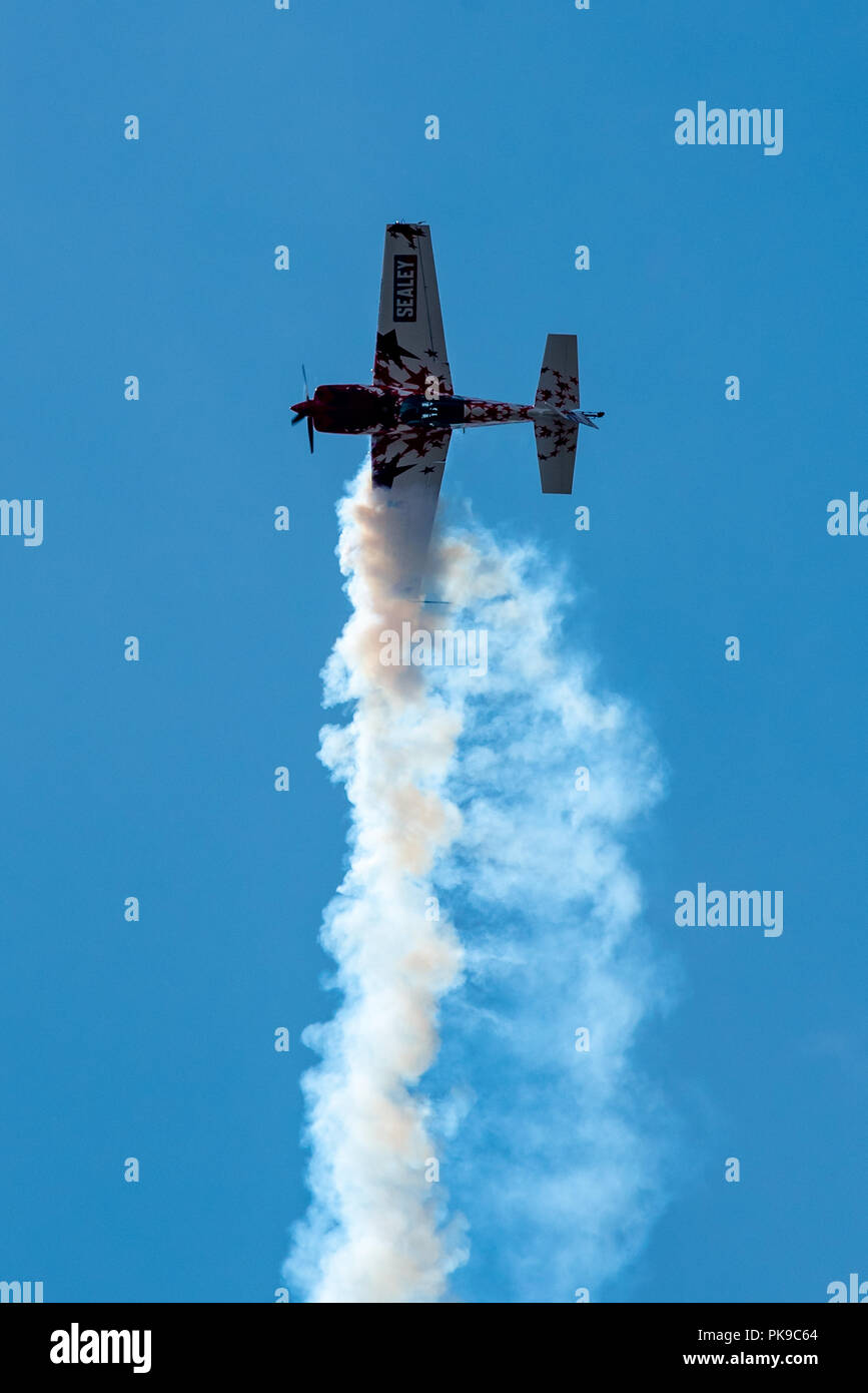 An inverted G-Force Aerobatics Extra 300 hangs at the top of a loop ...