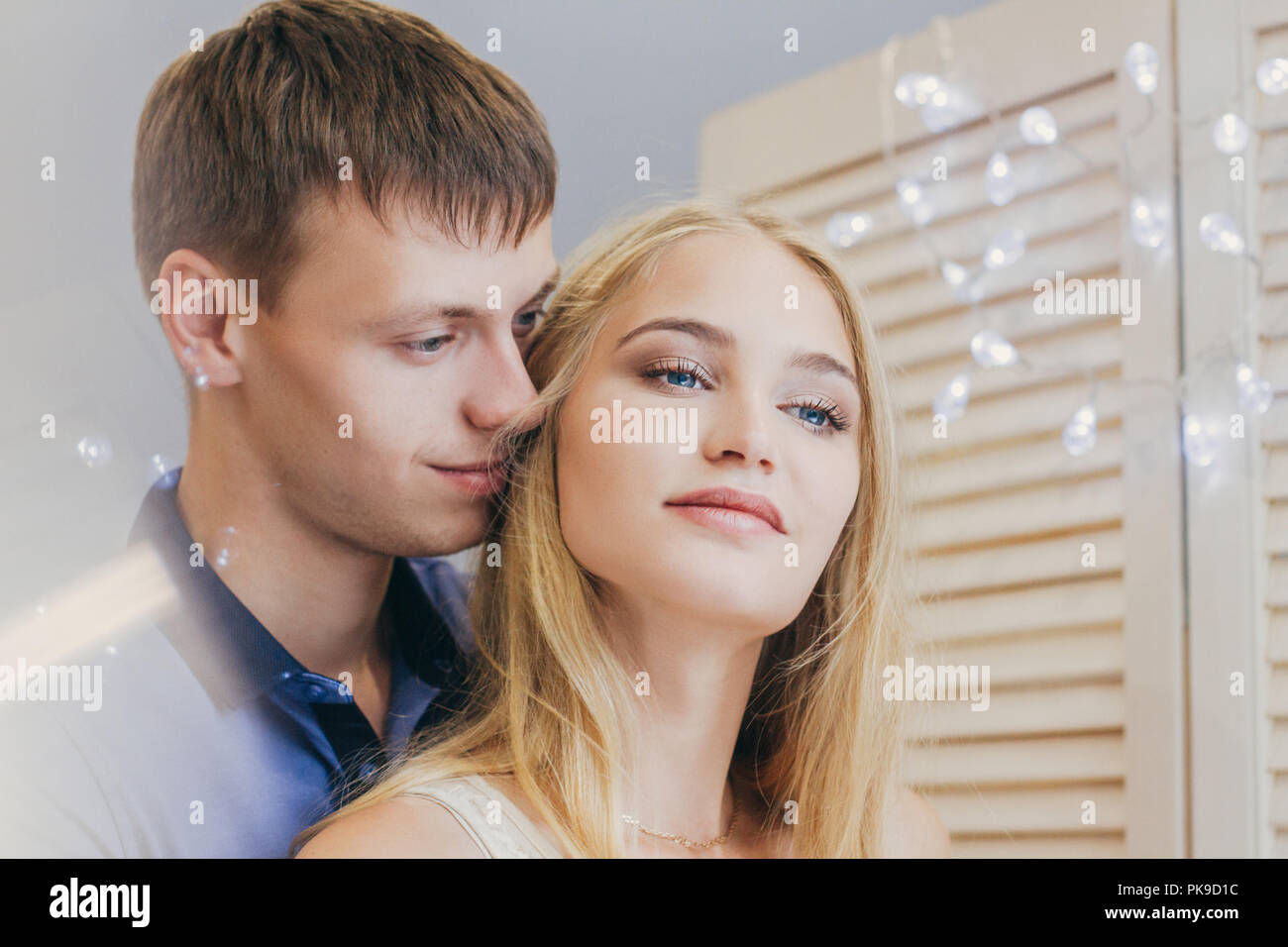 Beautiful loving couple looking out the window. Guy and girl cuddling ...