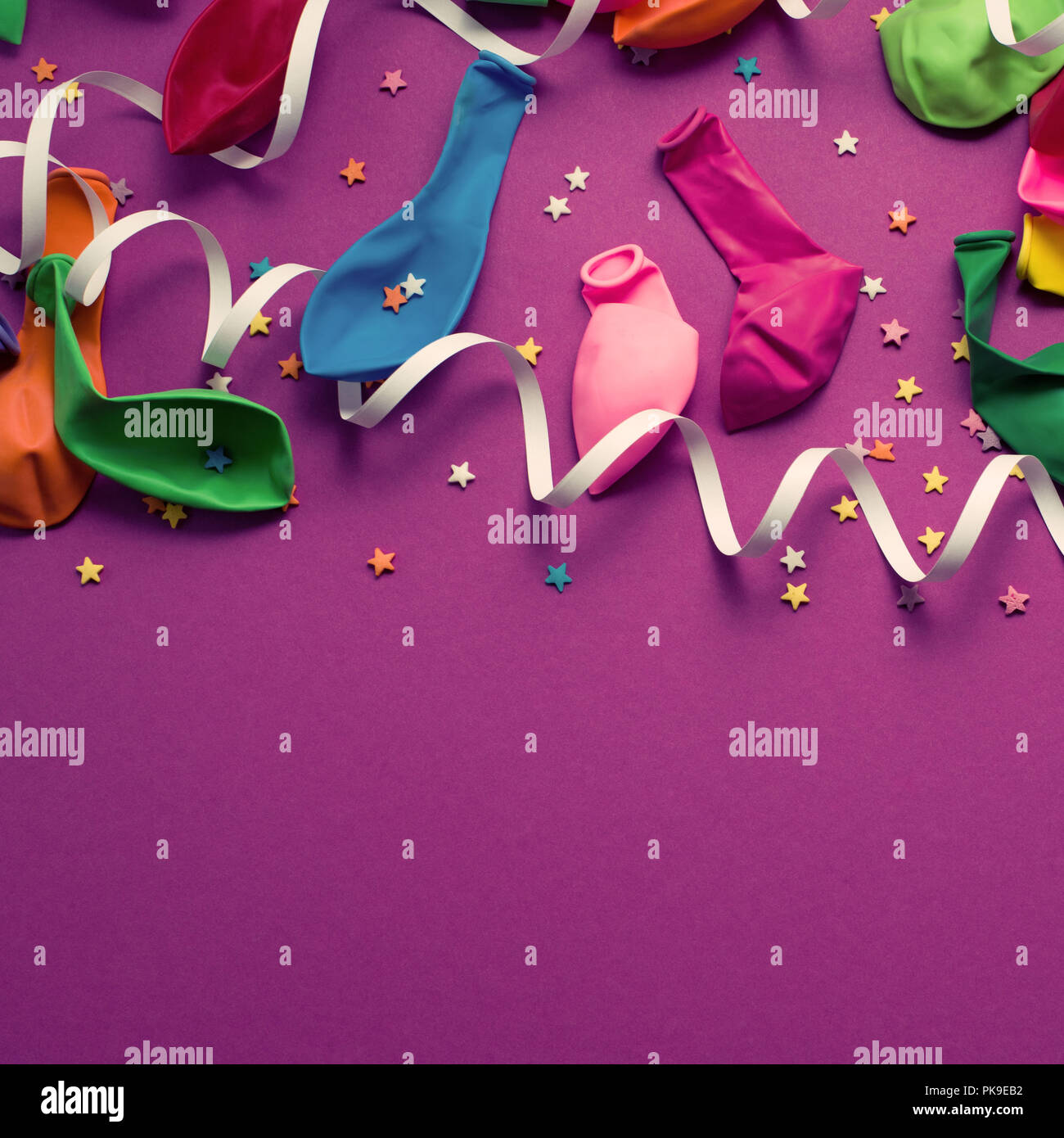 Festive background of purple material colorful balloons streamers ...
