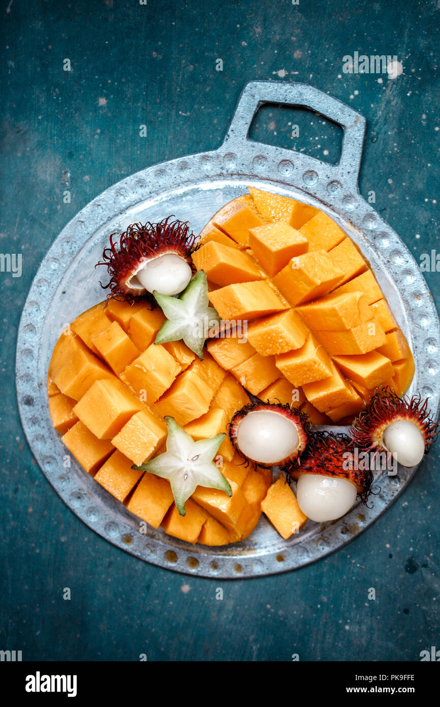 Juicy, ripe mango, rambutan and Cannon on a metal plate Stock Photo - Alamy