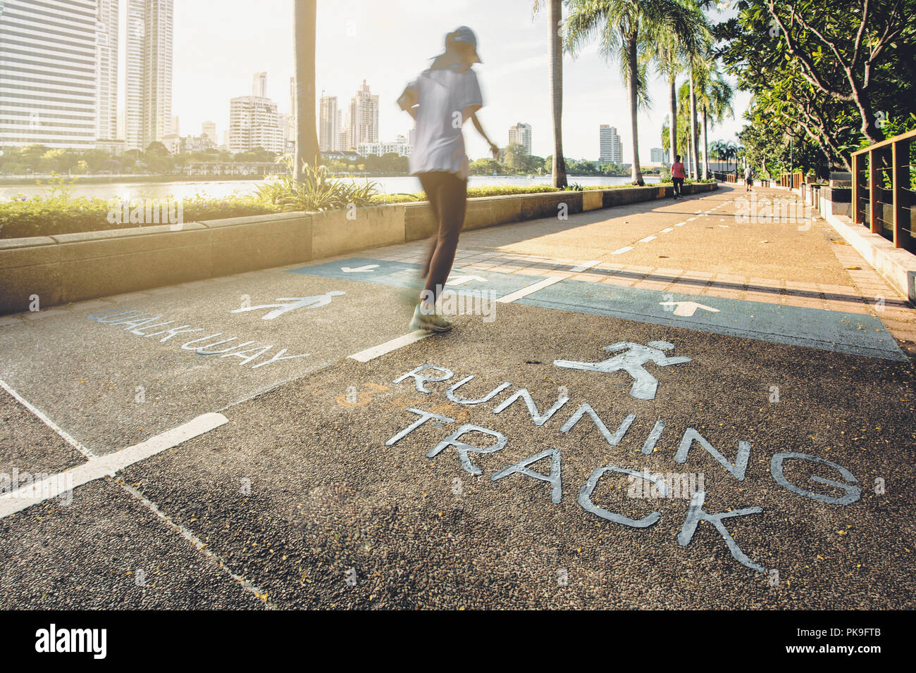 A woman runing on the running track way at public park in morning Stock ...