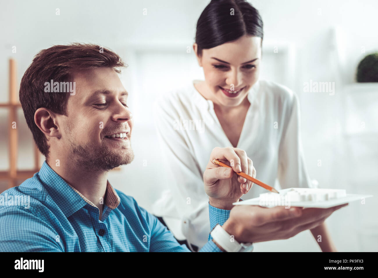 Pleased young man showing model of settlement Stock Photo - Alamy
