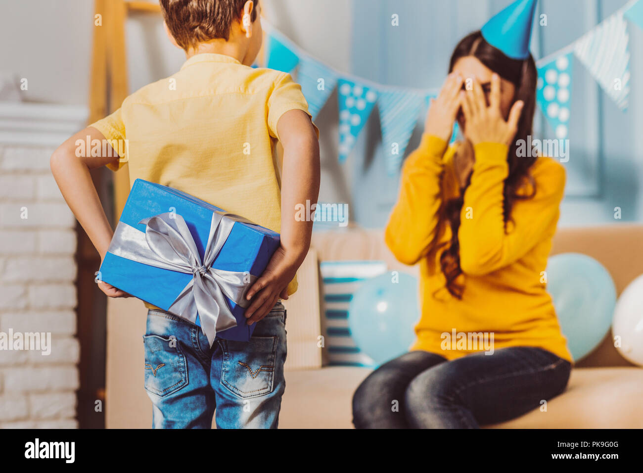 Boy hiding present for astonished mom Stock Photo - Alamy