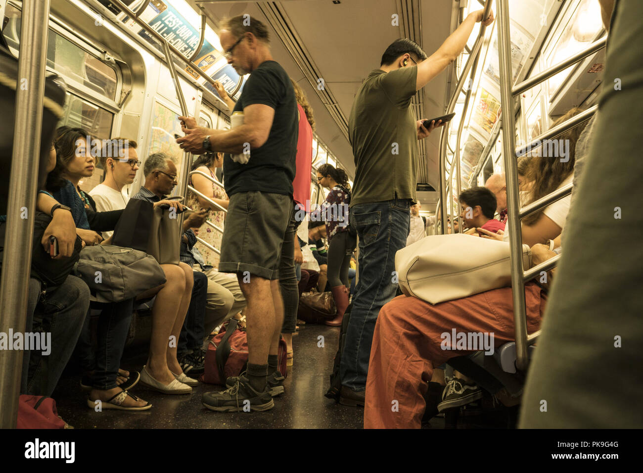 People standing and sitting on a crowded New York City subway train ...
