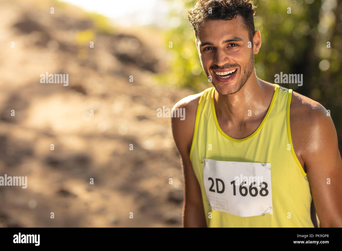 Portrait of a smiling male athlete in mountain trail race. Fit young ...