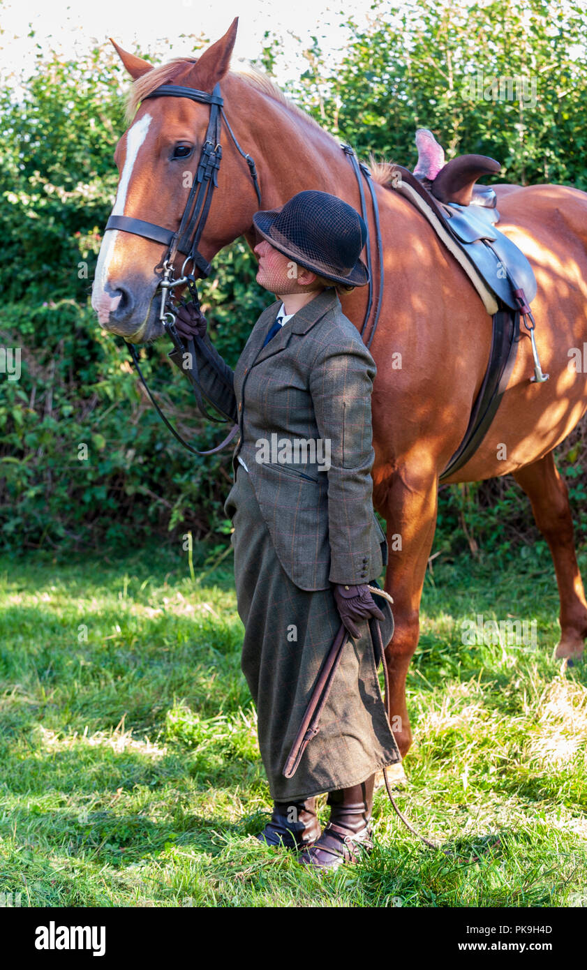 An elegent young lady riding in a traditional side saddle wearing ...