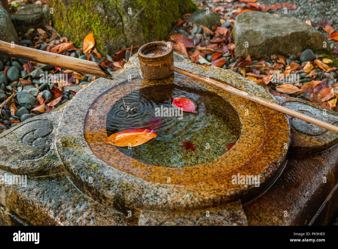 Old stone chozubachi for ritual ablution in Japan, with bamboo ladle ...