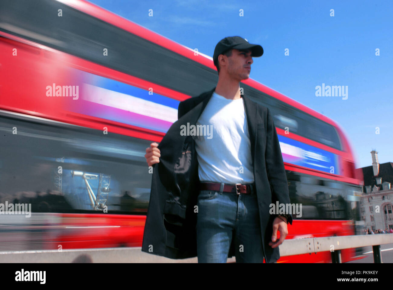 Young man standing next to a moving bus in casual clothing in a city ...