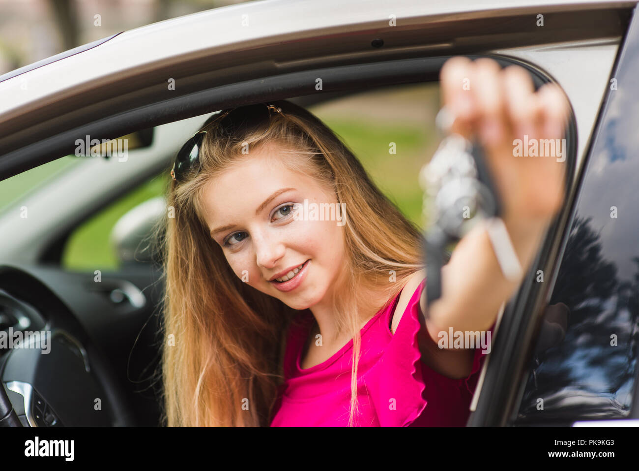 Girl inside vehicle with key in hand close up. Portrait of girl look at ...