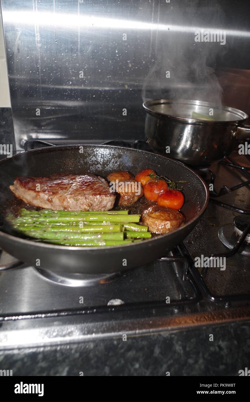 Steak Dinner Frying in a Pan. Home Cooking, UK Stock Photo - Alamy