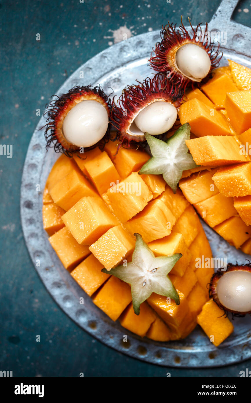 Juicy, ripe mango, rambutan and Cannon on a metal plate Stock Photo - Alamy