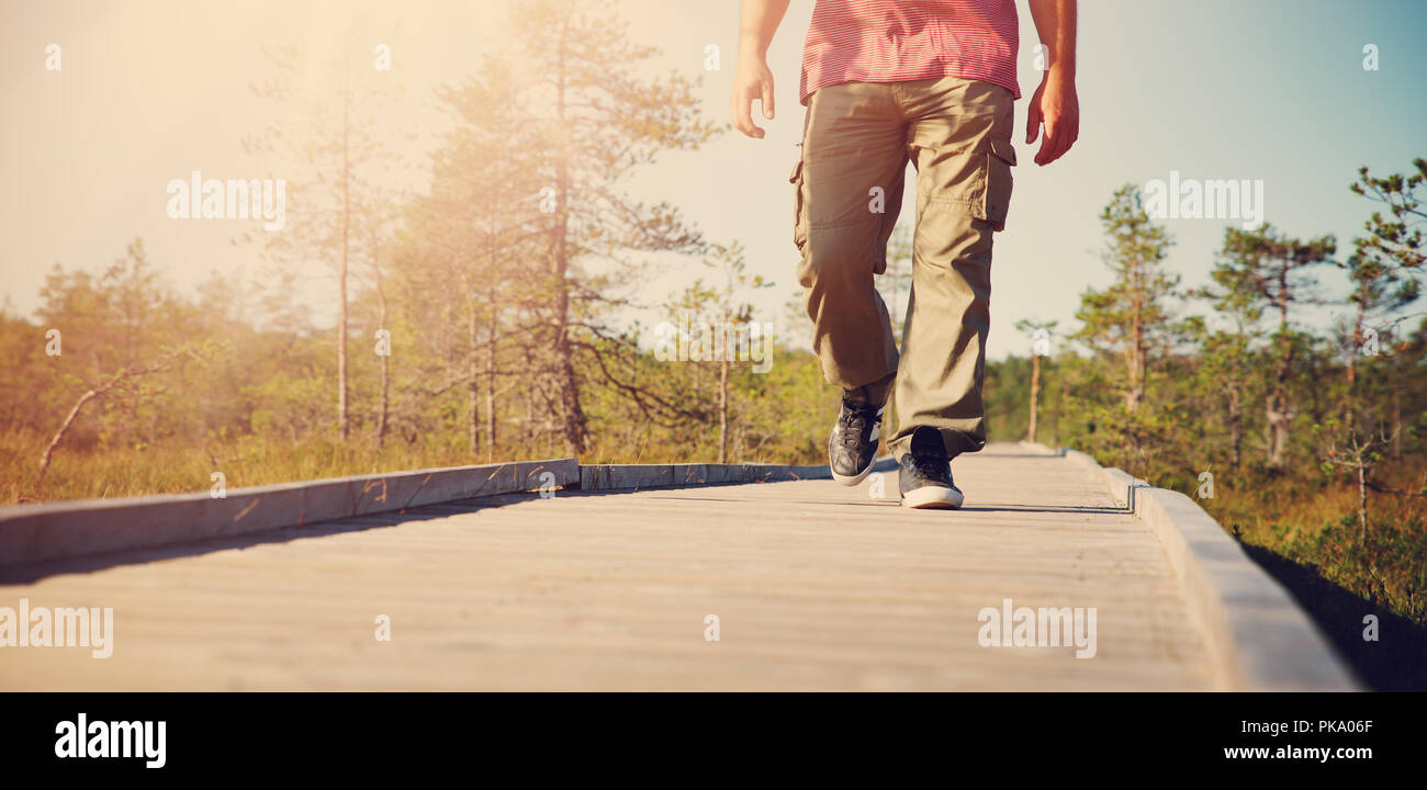 Man walking on wooden walkway in nature Stock Photo - Alamy