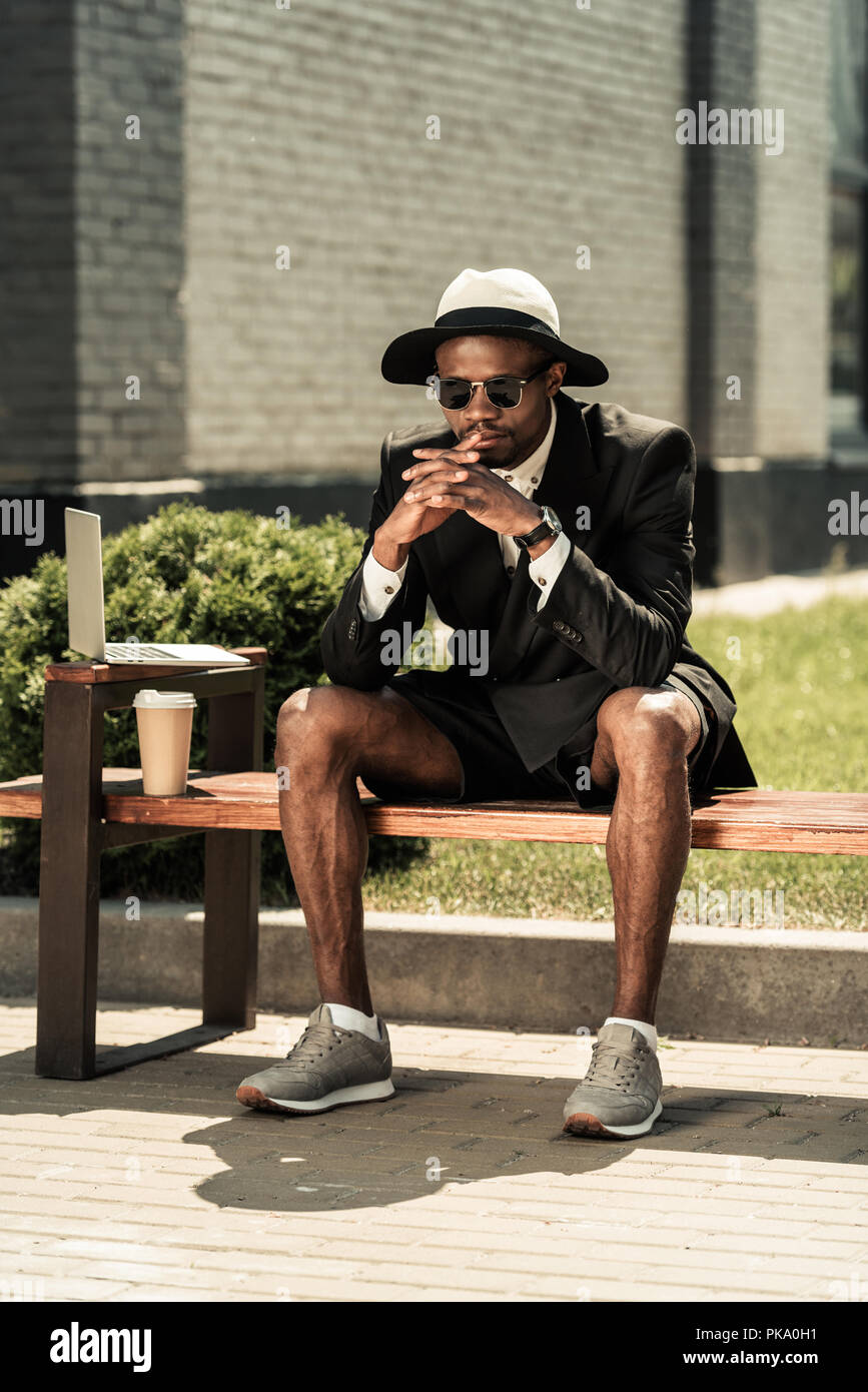 Handsome young african american man resting on bench by laptop Stock ...