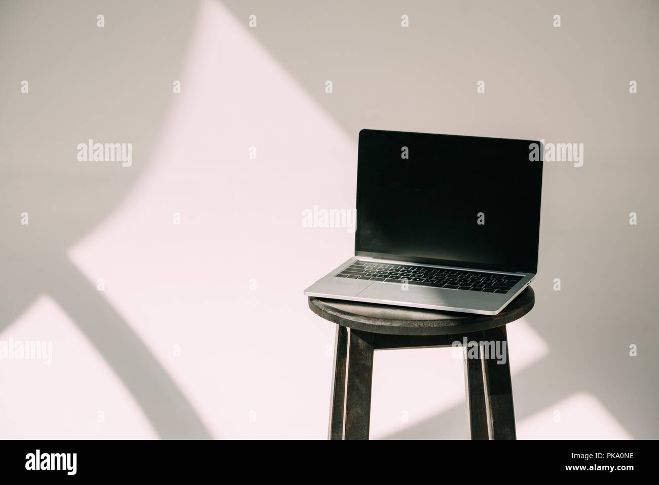 open laptop with black screen on stool on grey Stock Photo - Alamy